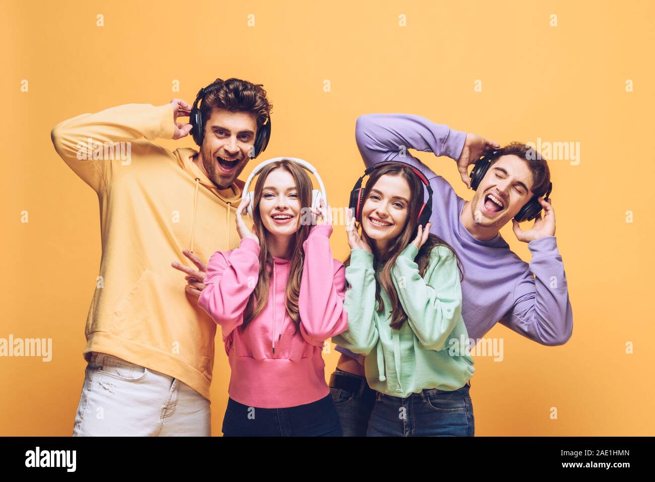 smiling friends listening music in headphones and dancing together ...