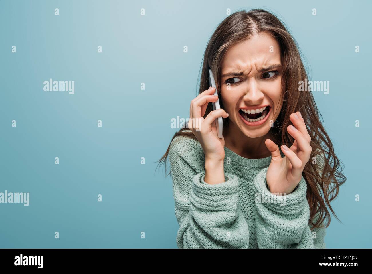 aggressive woman screaming and talking on smartphone, isolated on blue ...