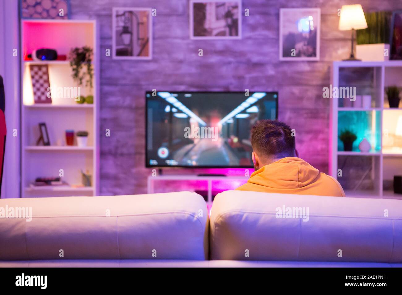 Back view of young man playing video games on television sitting on ...