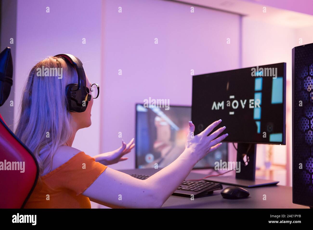 Blond girl can't belive while she lost on shooter game. Girl sitting on ...