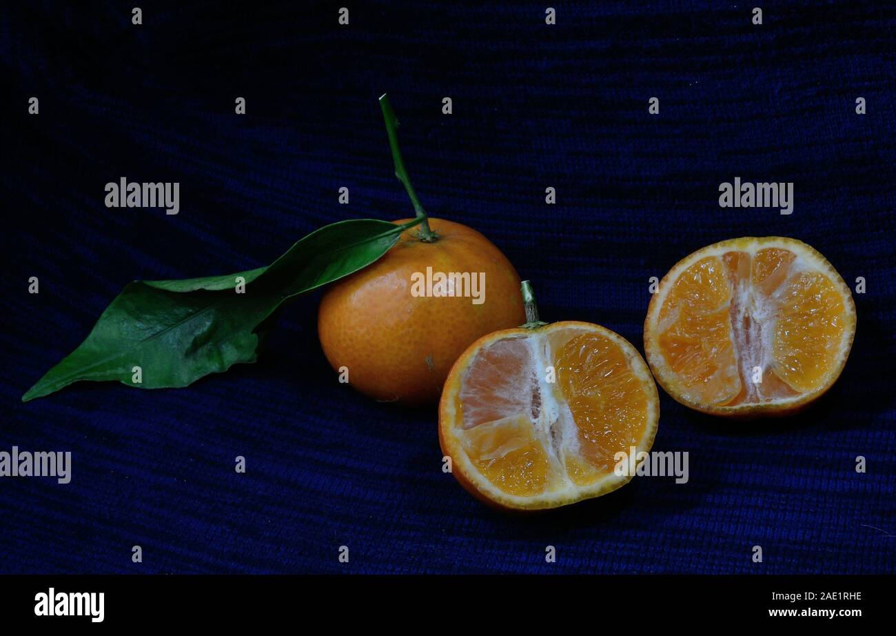 tangerine whole and open-face with leaf on dark blue background Stock ...
