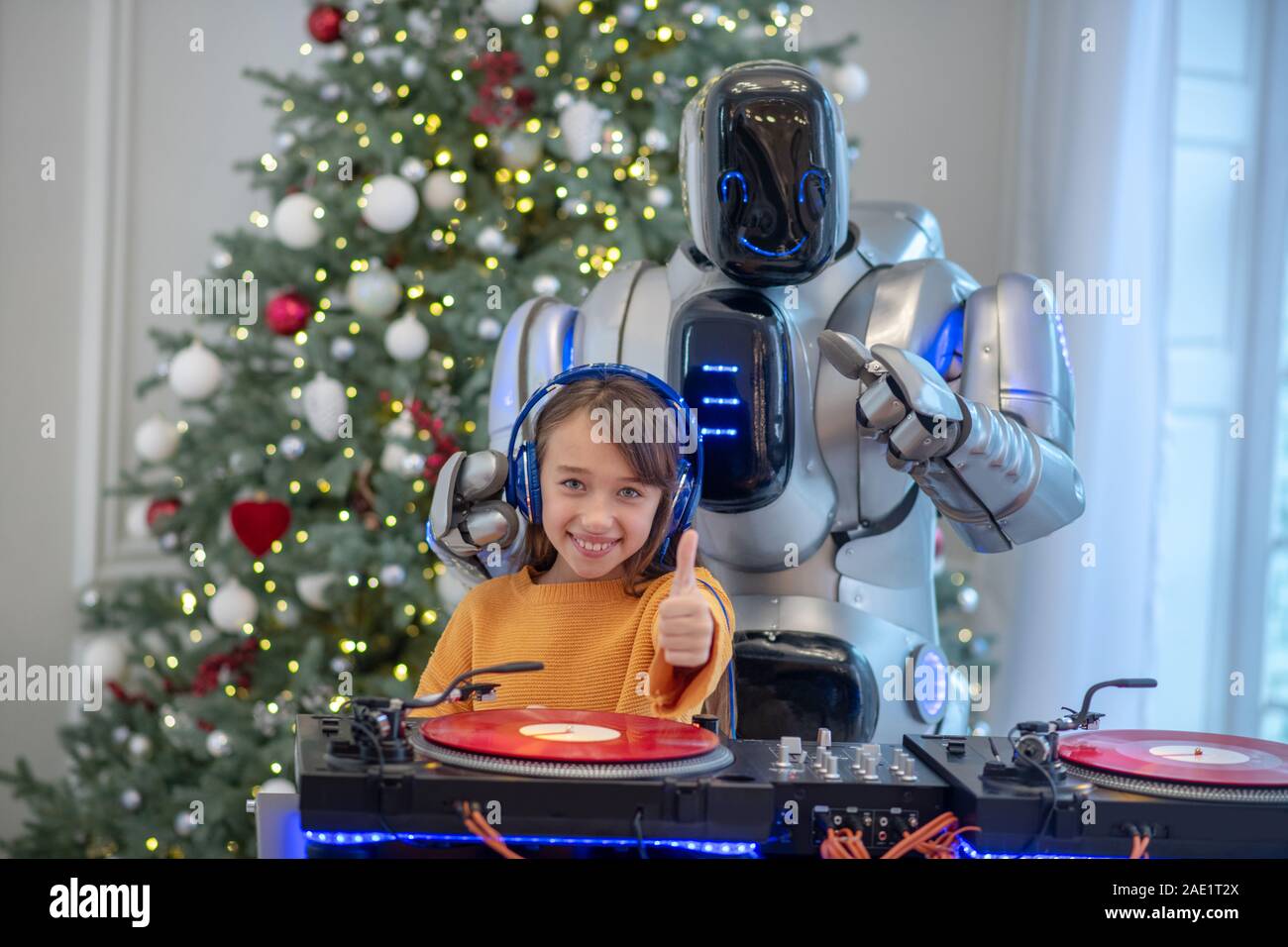 Pretty girl and robot standing near the new year tree Stock Photo - Alamy