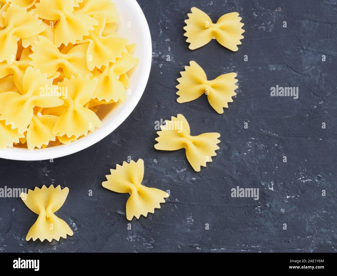 Pasta bow type in wooden bowl on a black concrete background with copy ...
