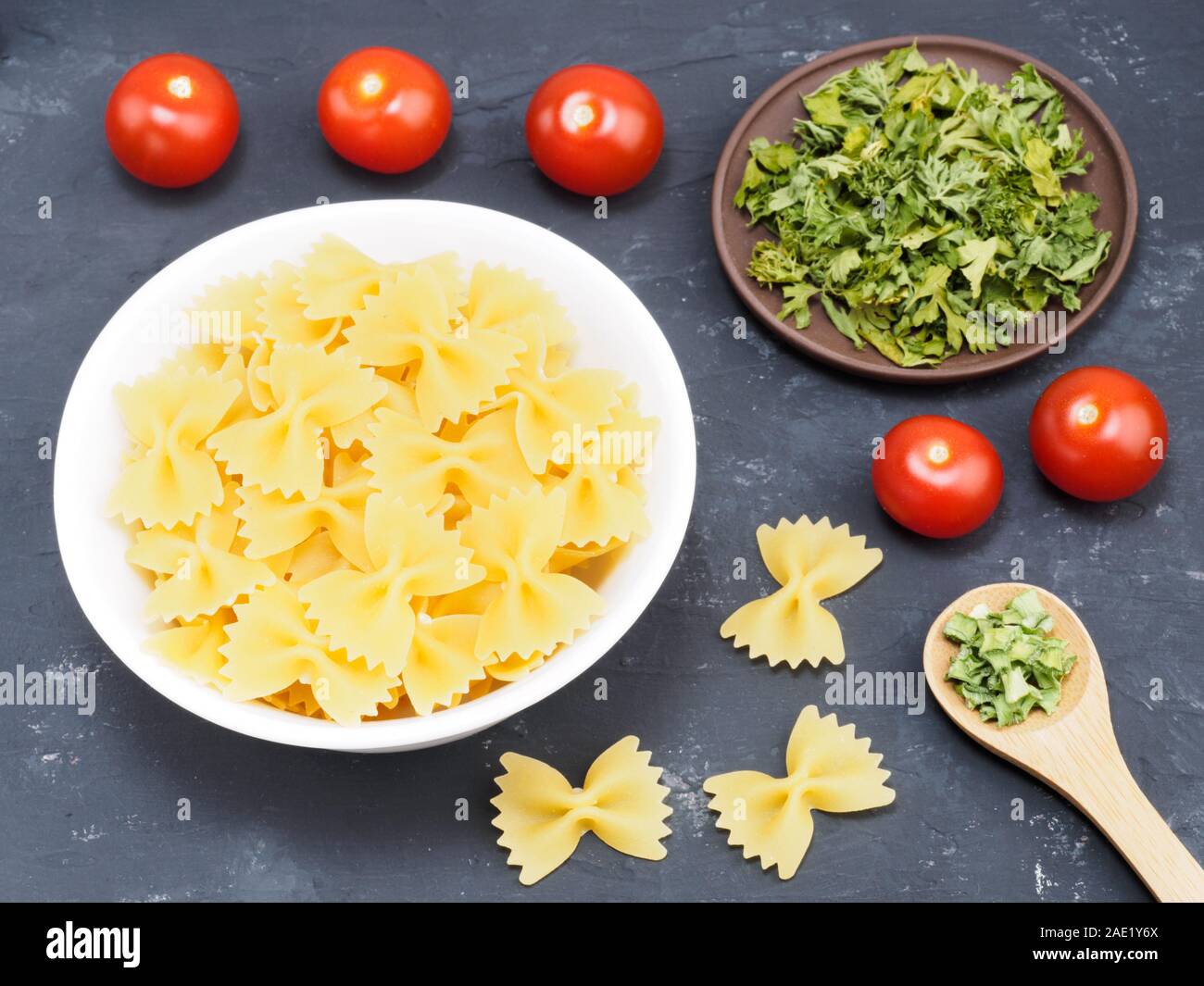Pasta in white bowl, small tomatoes, green grass on a black concrete ...