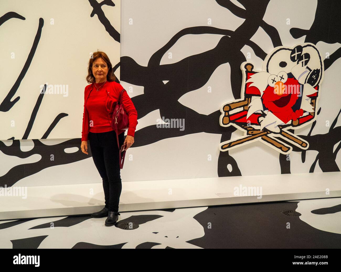 Woman standing by art by Brian Donnelly aka KAWS sculptor and graffiti ...
