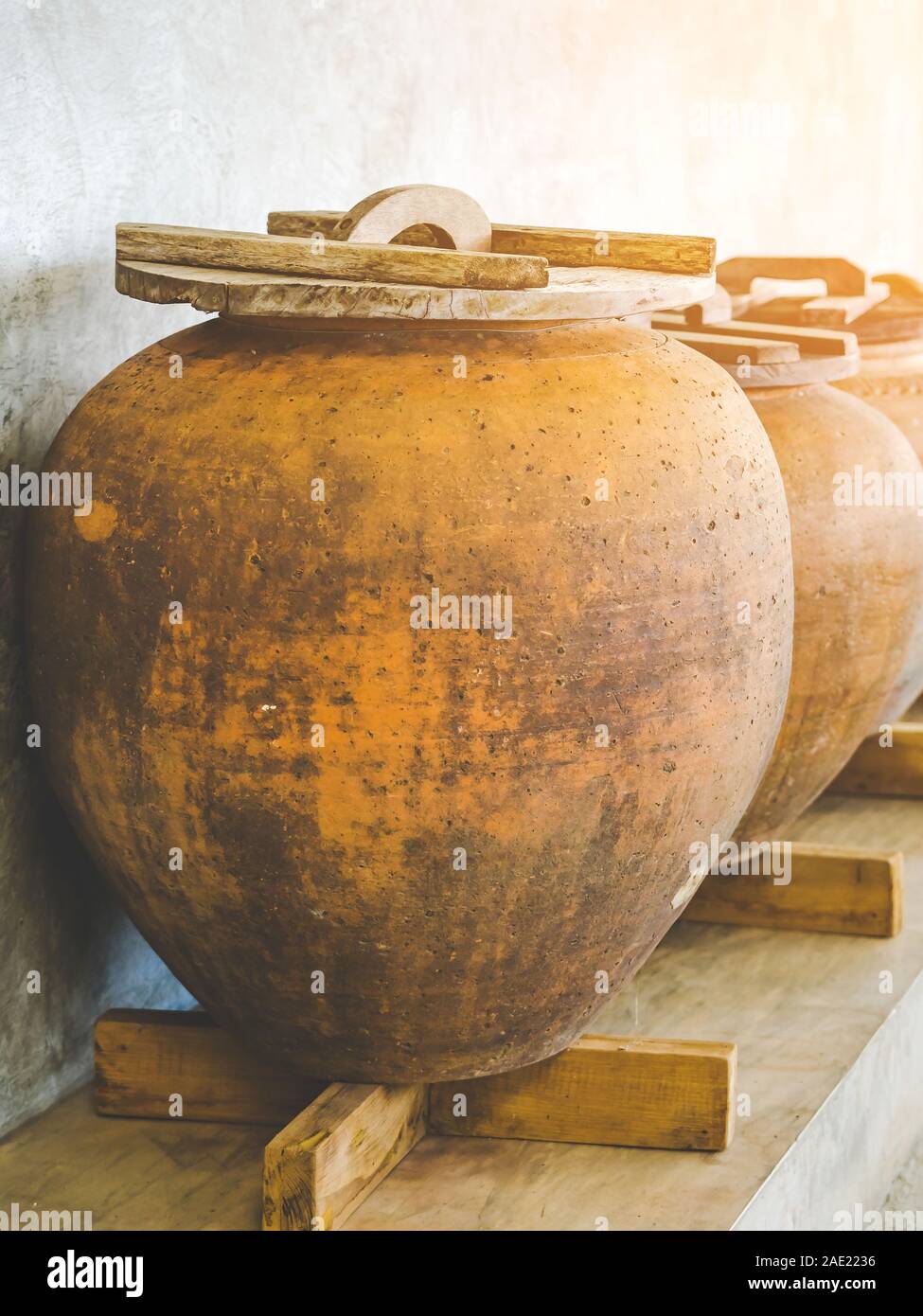Row of earthen jars with wood lids and rough gray floor for water ...