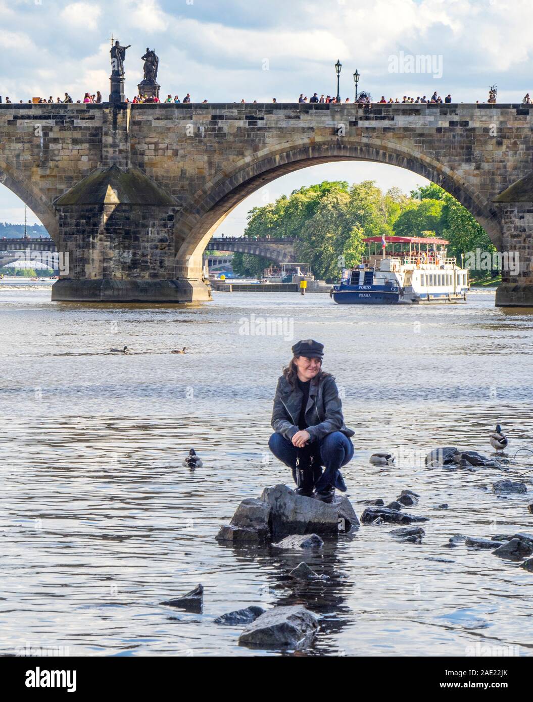 Caucasian female tourist posing for photo by crouching on a rock in the ...