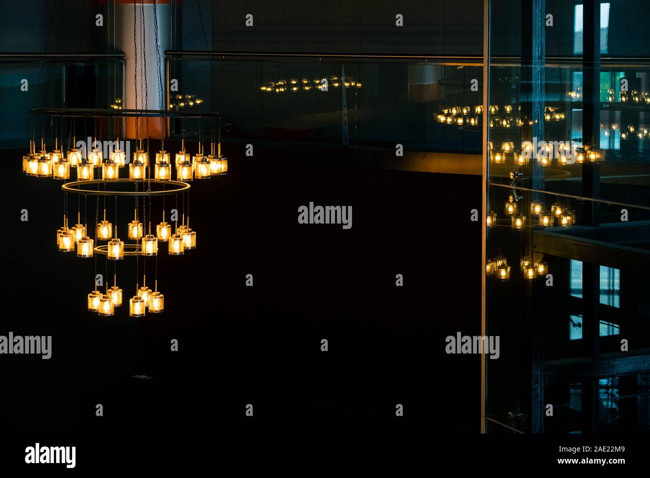 Big chandelier with yellow lights pending in a high ceiling building ...