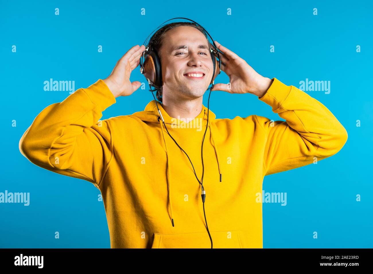 Handsome man with headphones dancing isolated on blue background. Party ...