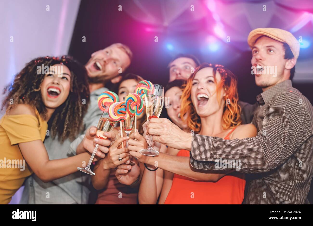 Happy friends having fun toasting with champagne and eating lollipops ...