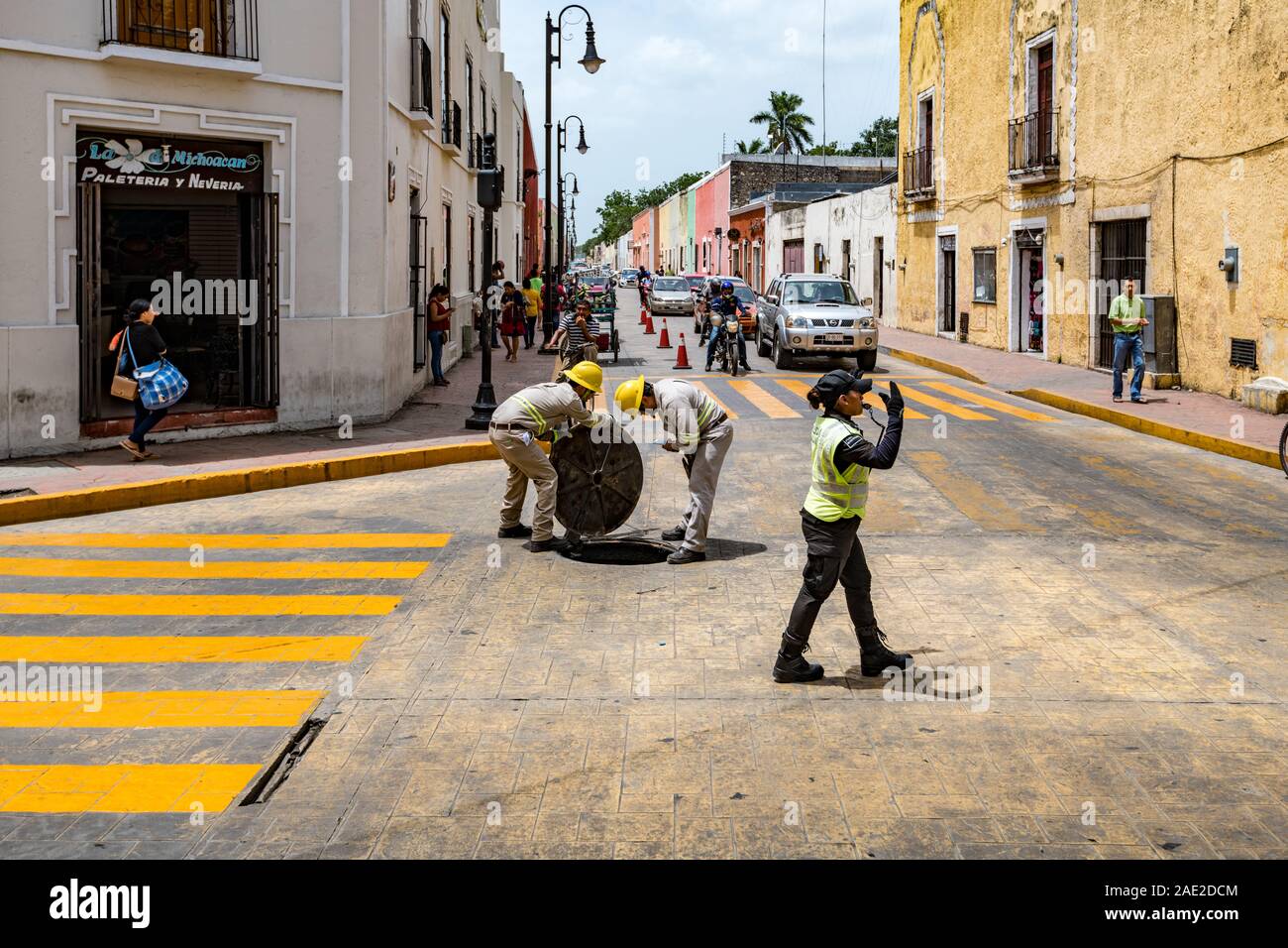 Mexican police woman directing traffic, with workmen lifting man hold ...