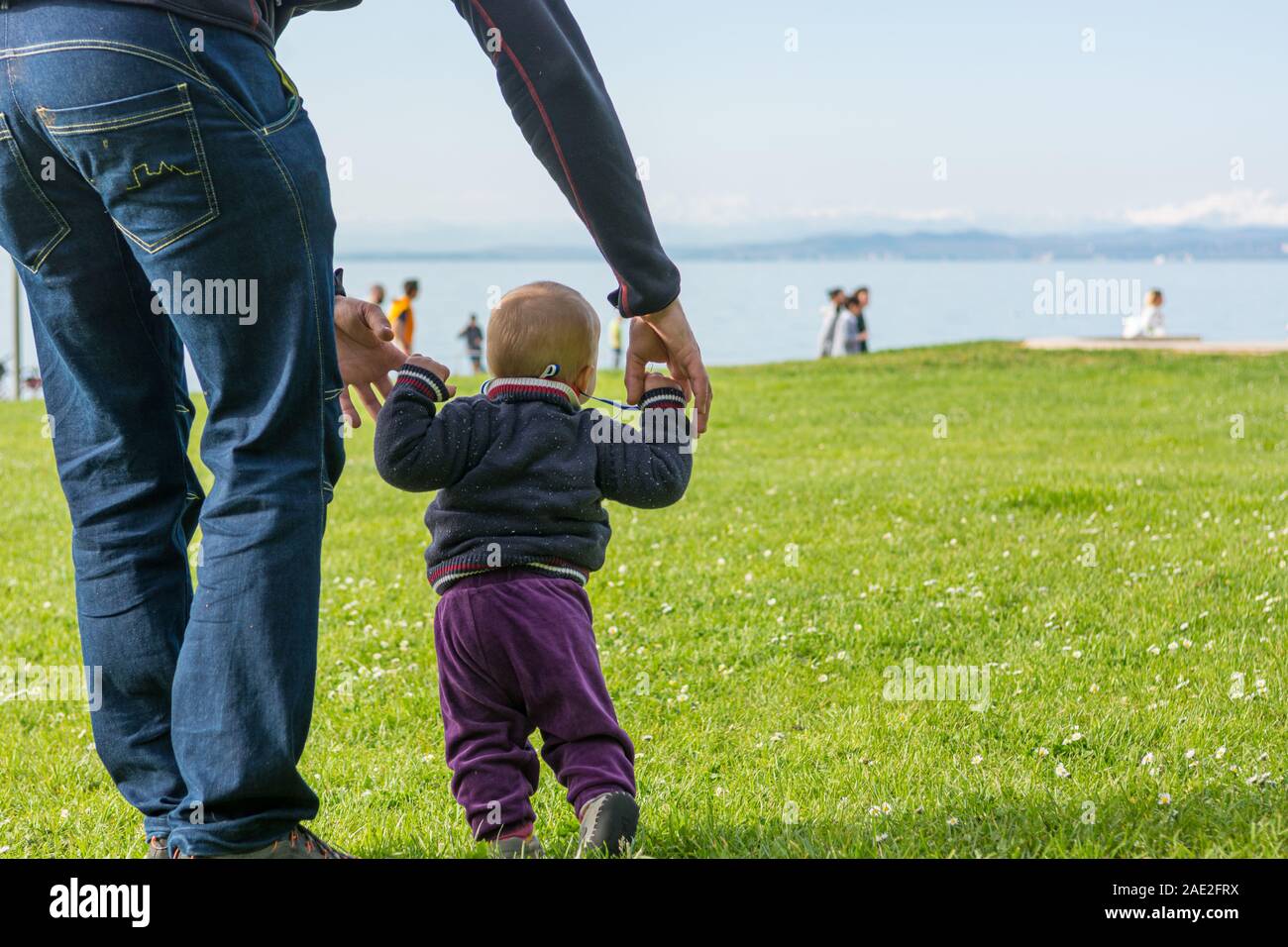 Cute baby girl learning to walk with her father in a park Stock Photo ...
