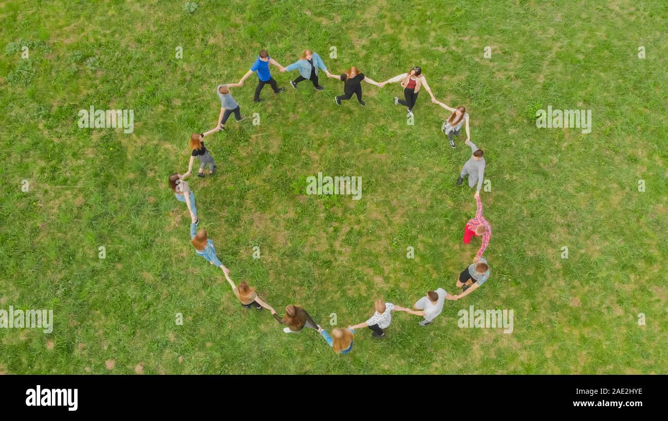 Friends in a circle holding hands make a round dance in the field Stock ...