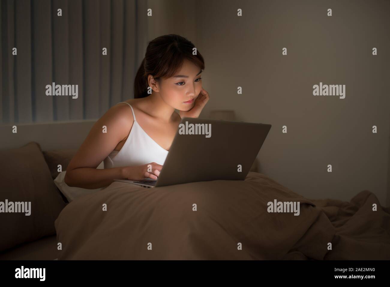 Woman looking at laptop in bed Stock Photo - Alamy