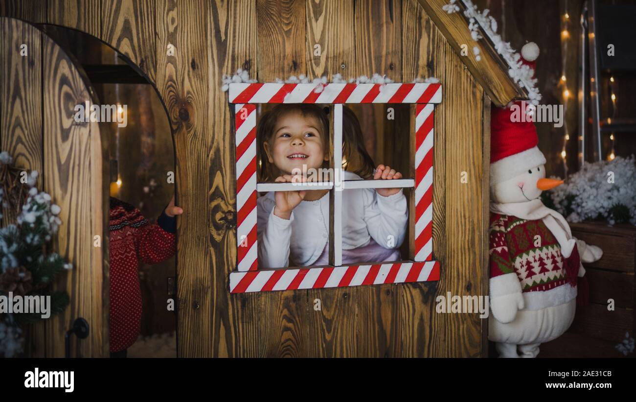 Funny little toddler girl peeping out the window playing with snow ...
