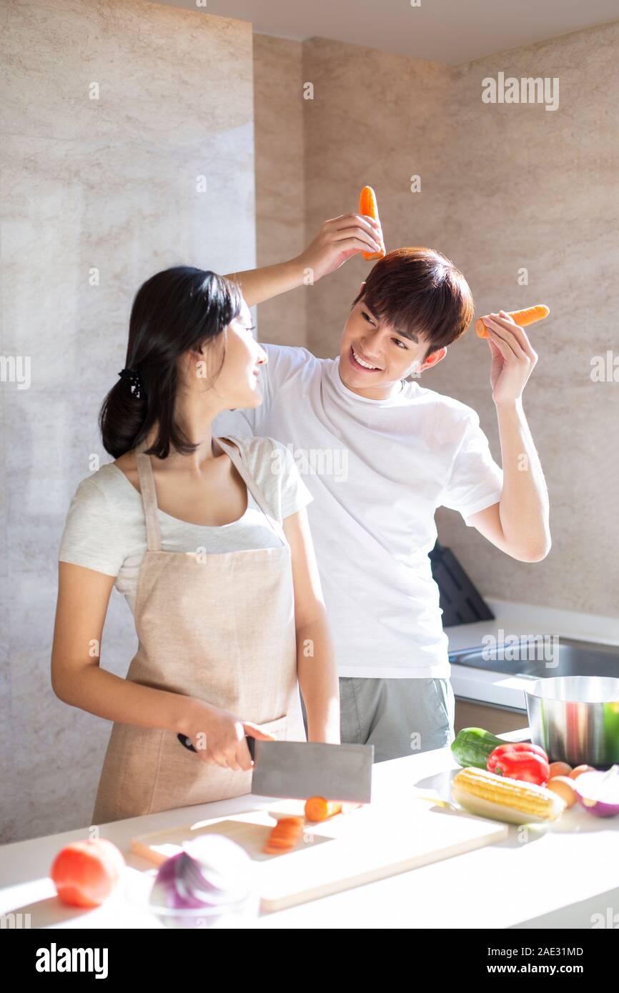Happy young couple cooking in kitchen Stock Photo - Alamy