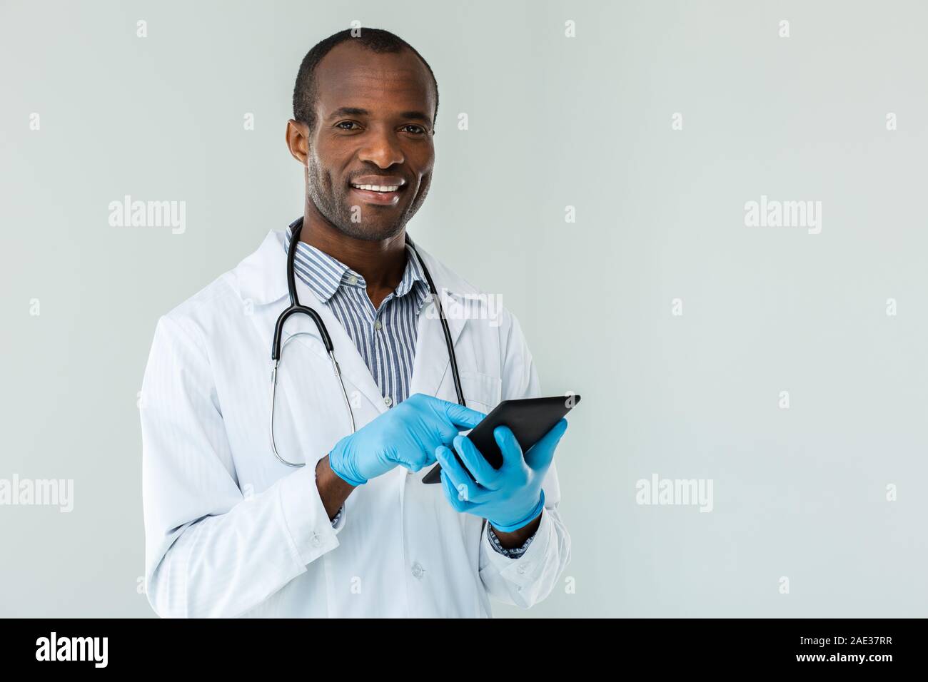 Waist up of cheerful doctor holding his tablet Stock Photo - Alamy