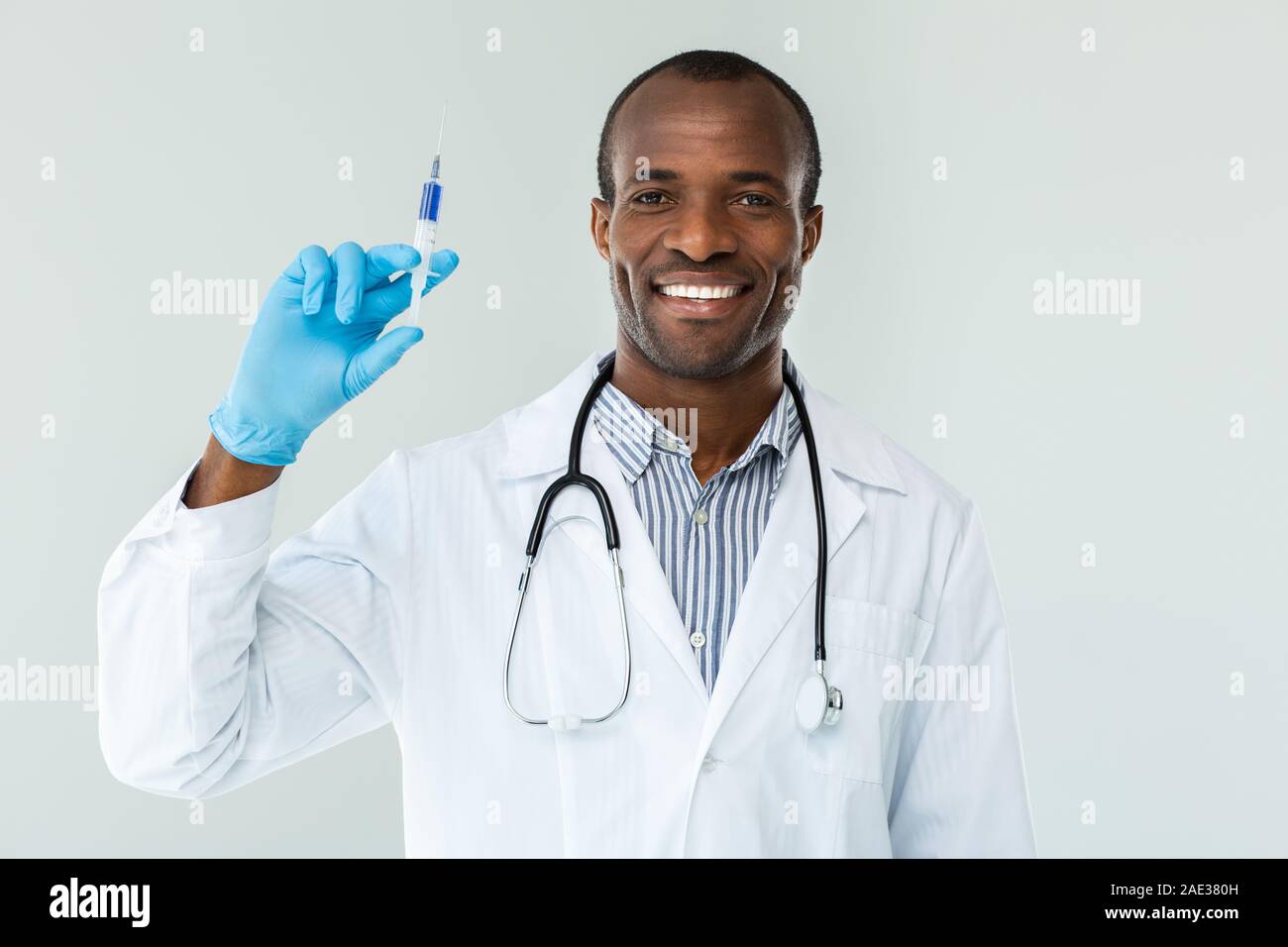 Positive smiling doctor holding a syringe Stock Photo - Alamy