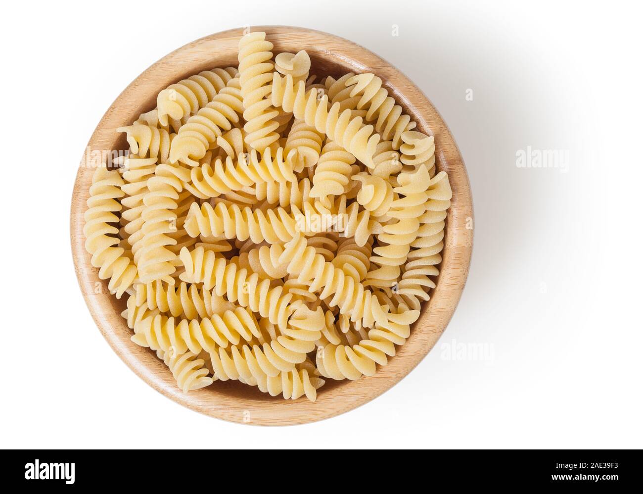 Uncooked fusilli pasta in wooden bowl isolated on white background with ...