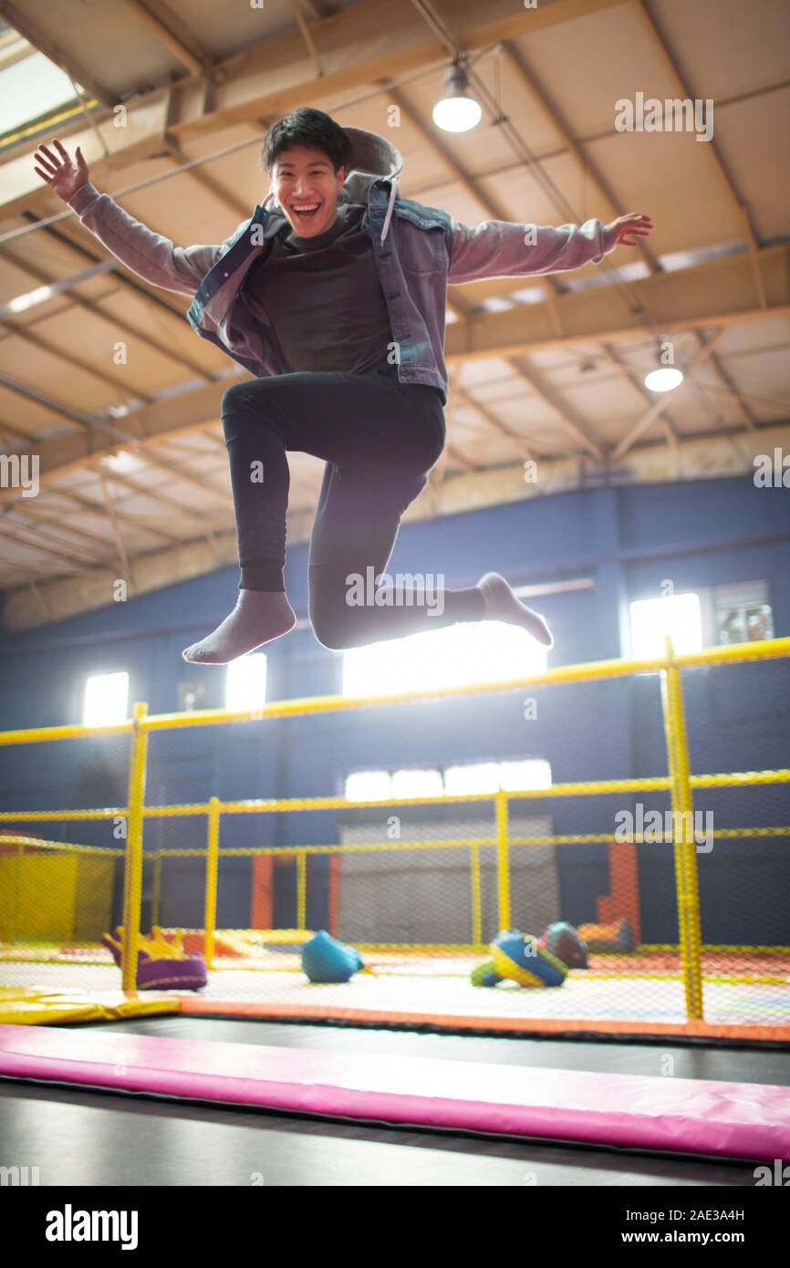Happy young man jumping on trampoline Stock Photo - Alamy