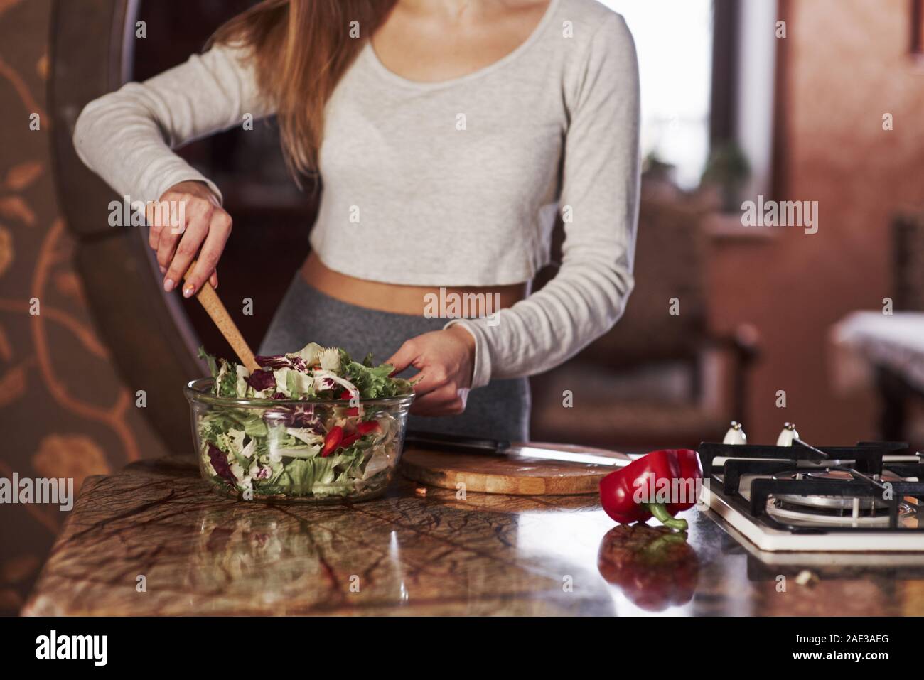 Mixing vegetables. Pretty young woman standing in the modern kitchen ...