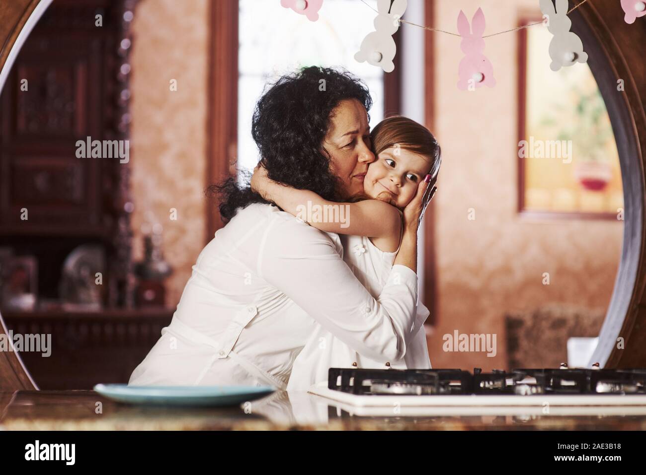 Spontaneous hug. Grandmother and granddaughter have fun at the kitchen ...