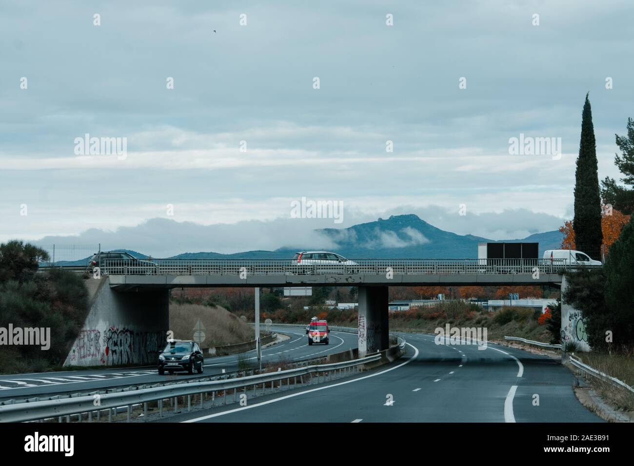 Two cars driving under a bridge on a typical Spanish highway in the ...
