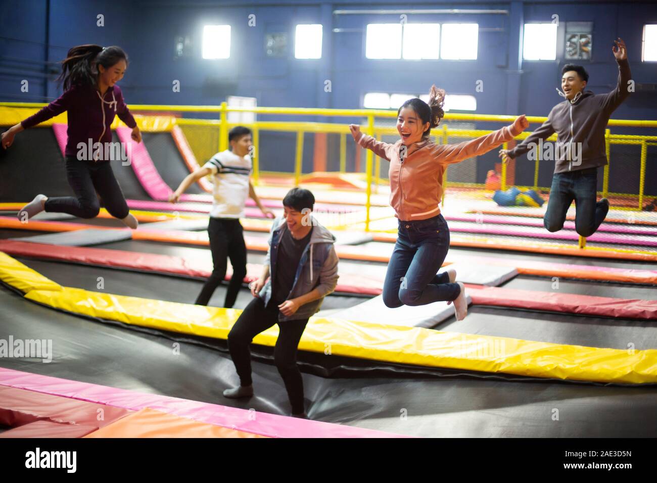 Happy young friends jumping on trampoline Stock Photo - Alamy