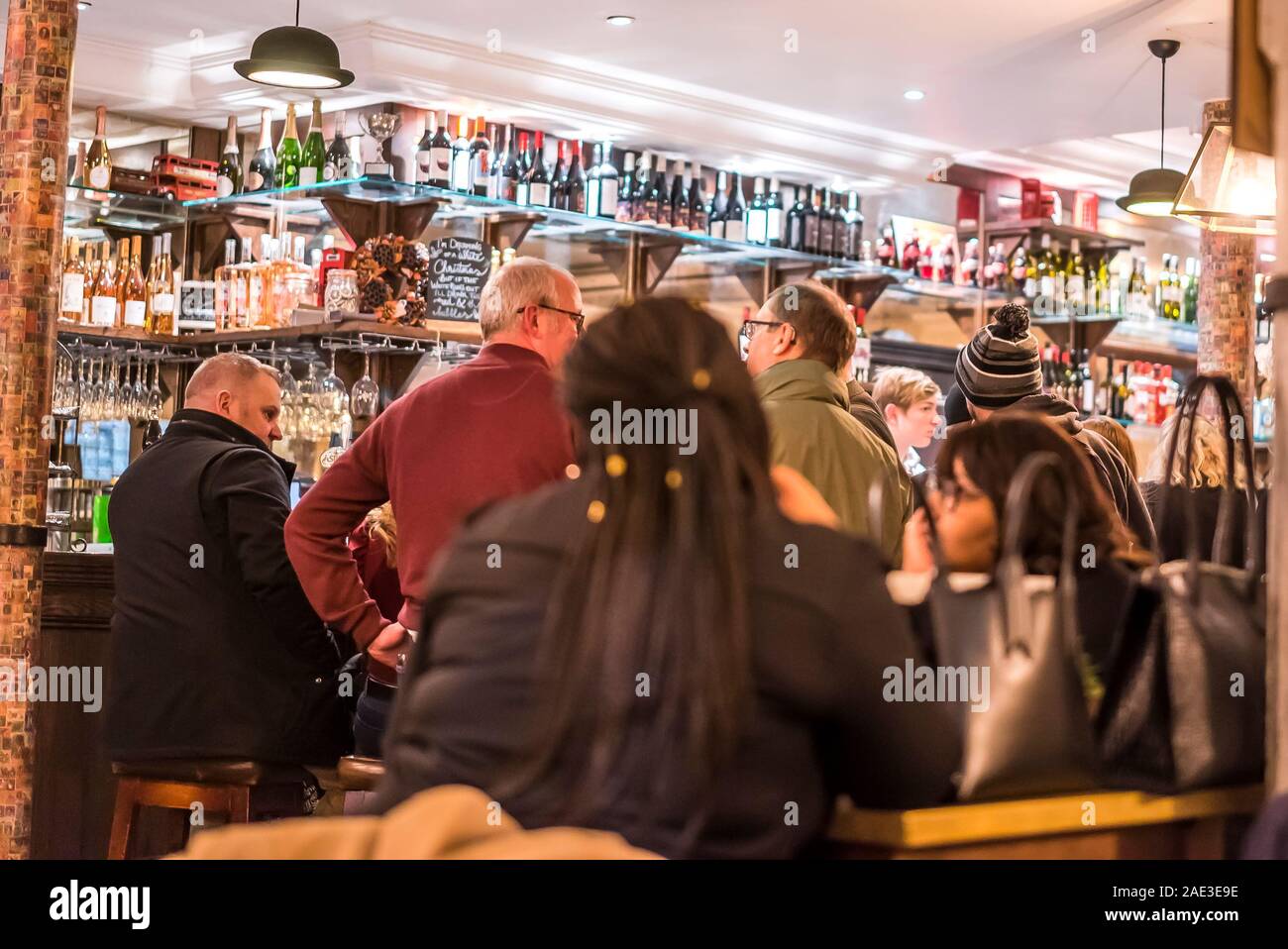 Rear view of people socializing, drinking inside central London bar ...