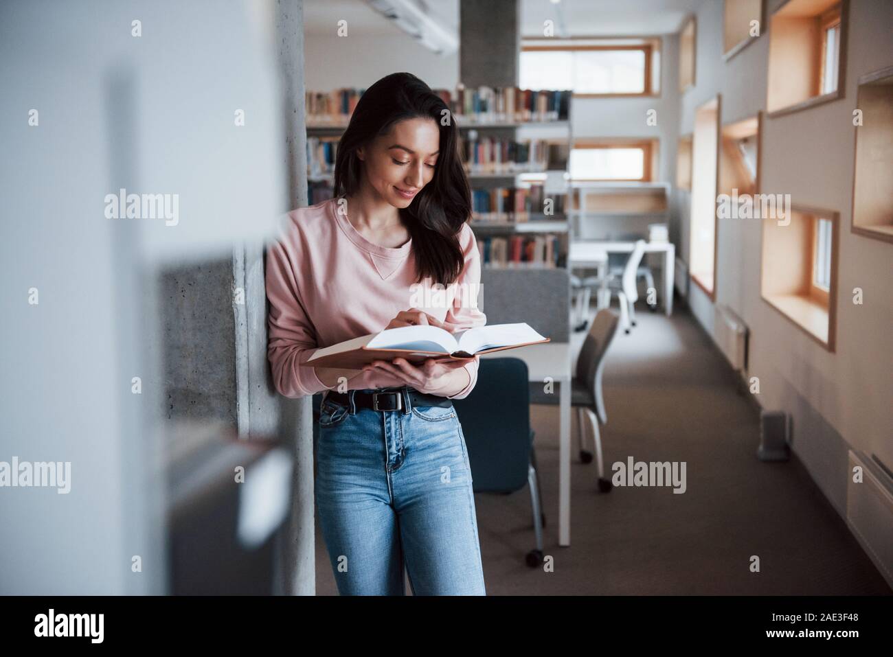 Standing and reading. Brunette girl in casual clothes having good time ...