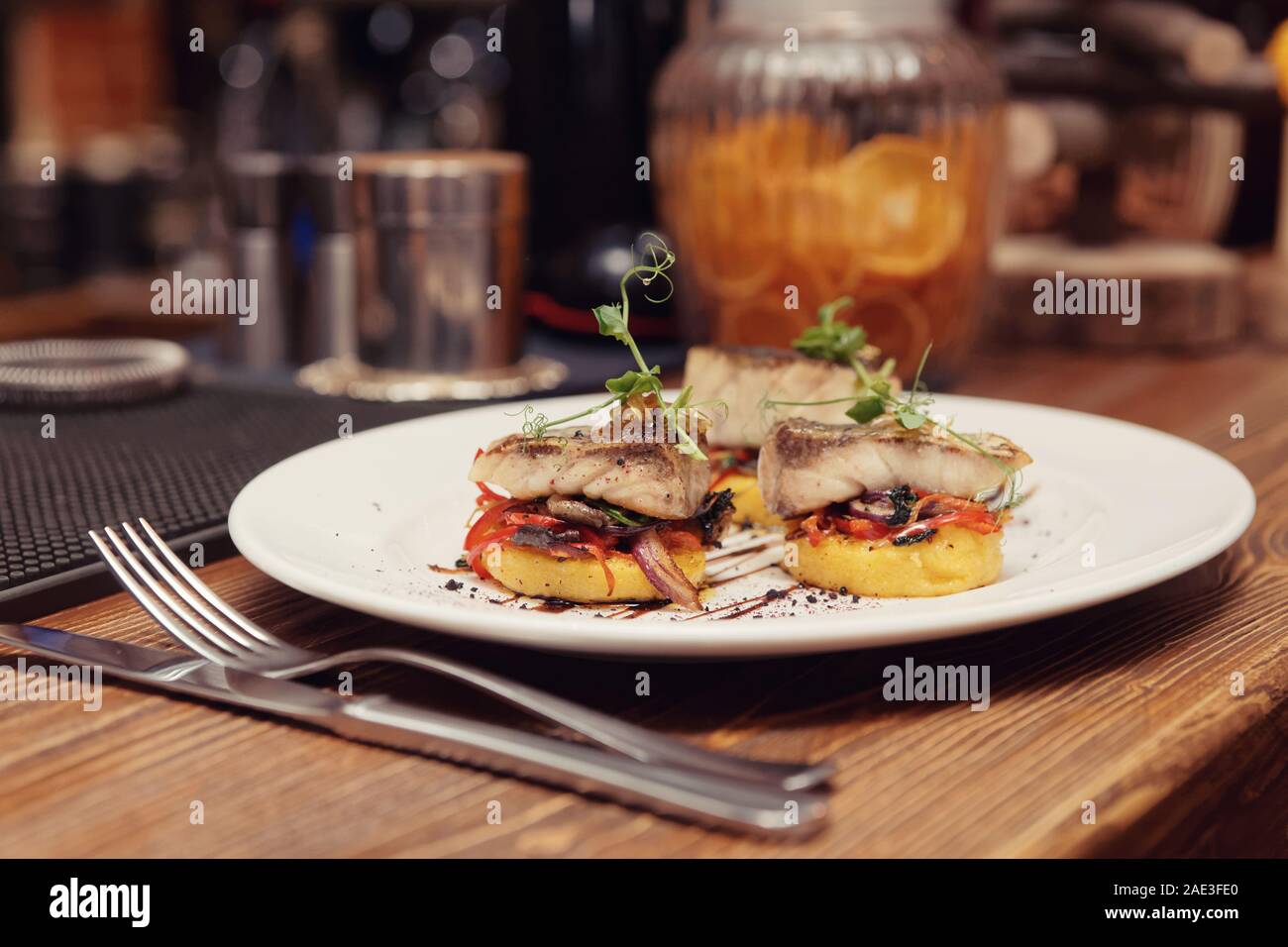 Fried fish fillet and polenta served on bar counter, toned image Stock ...