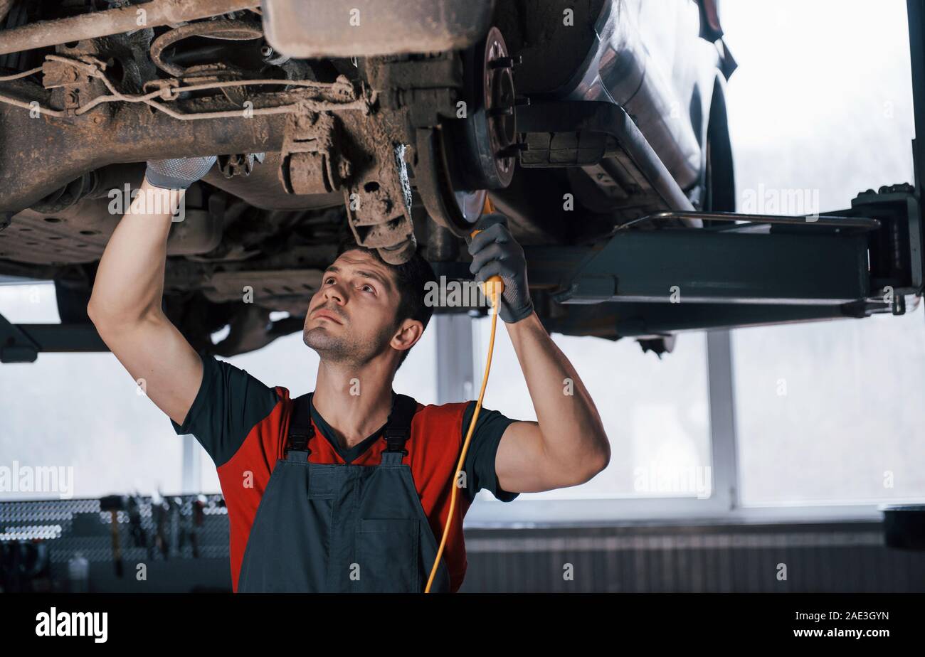 In process of repairing. Man at the workshop in uniform fixes broken ...