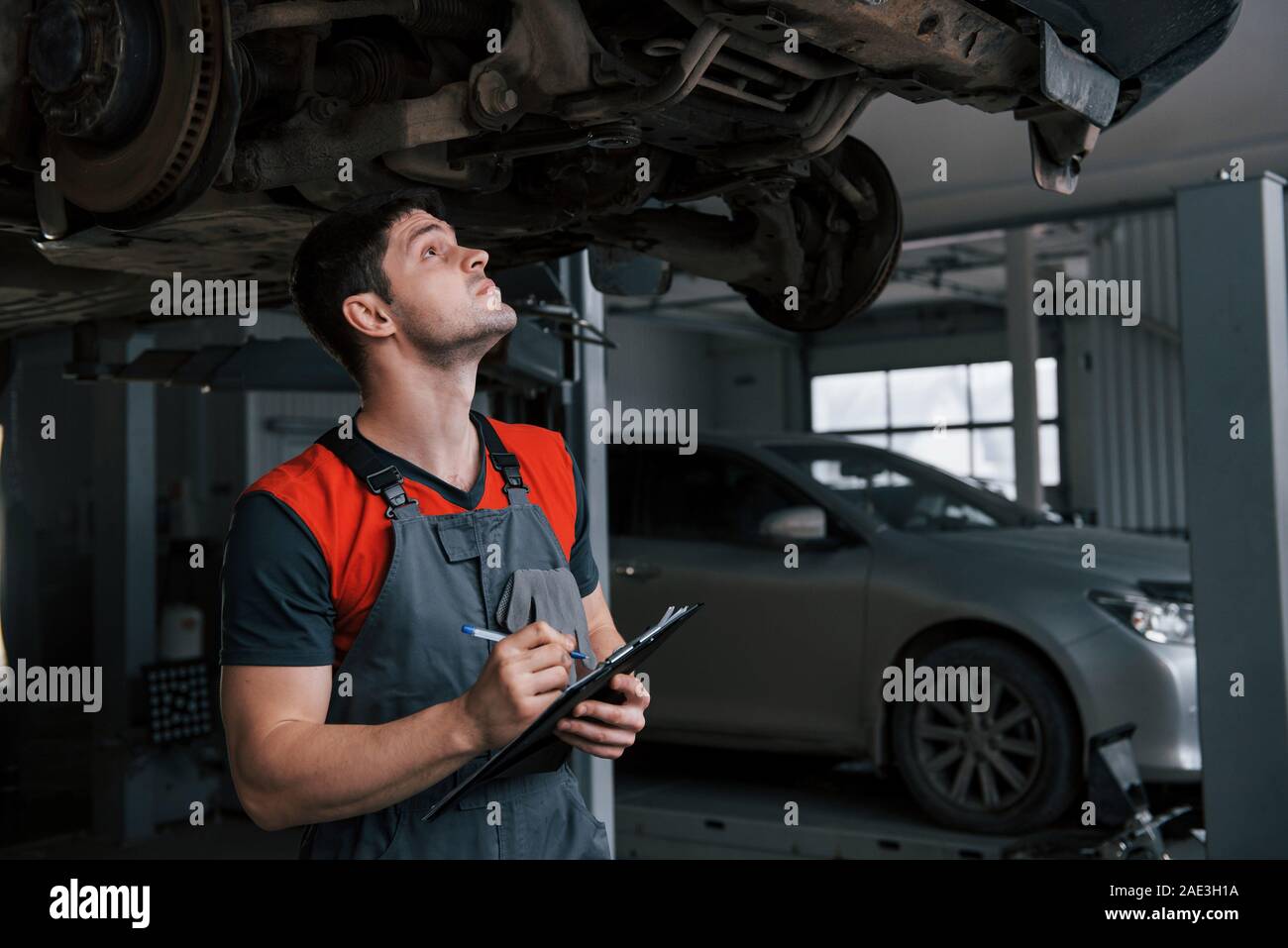 Evaluates damage. Man at the workshop in uniform using notepad for his ...