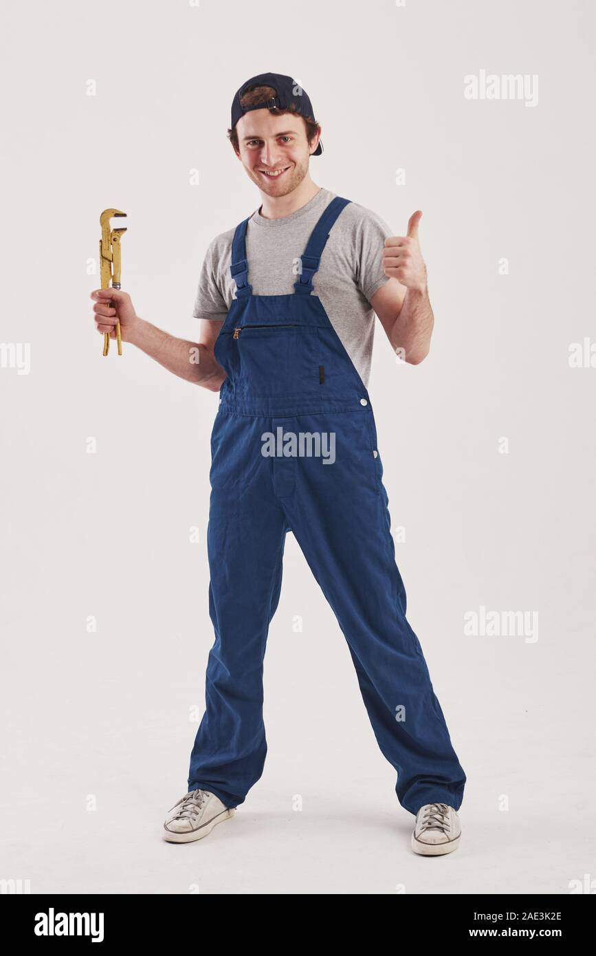 Happy worker. Man in blue uniform stands against white background in ...
