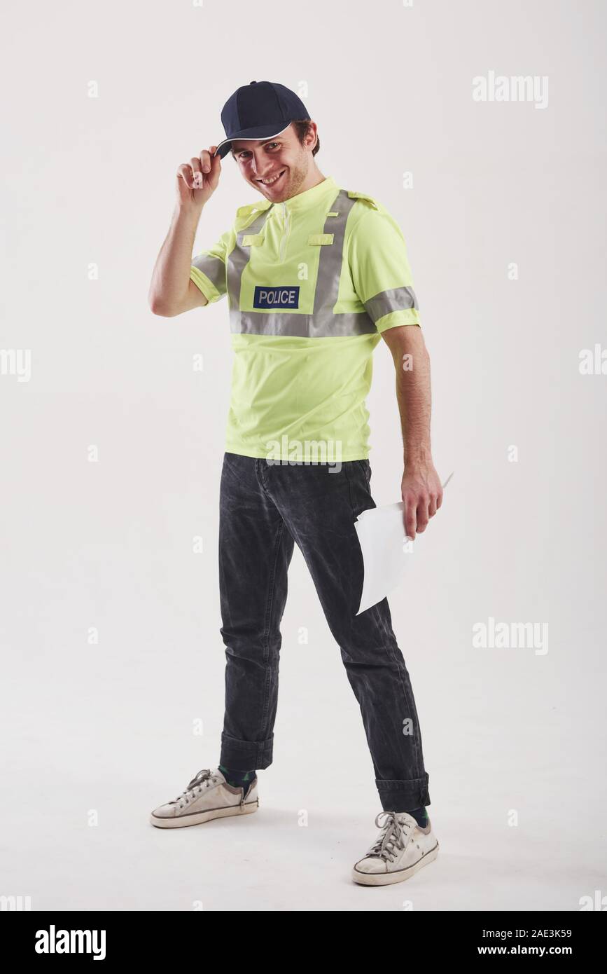 Having nice mood. Policeman in green uniform stands against white ...