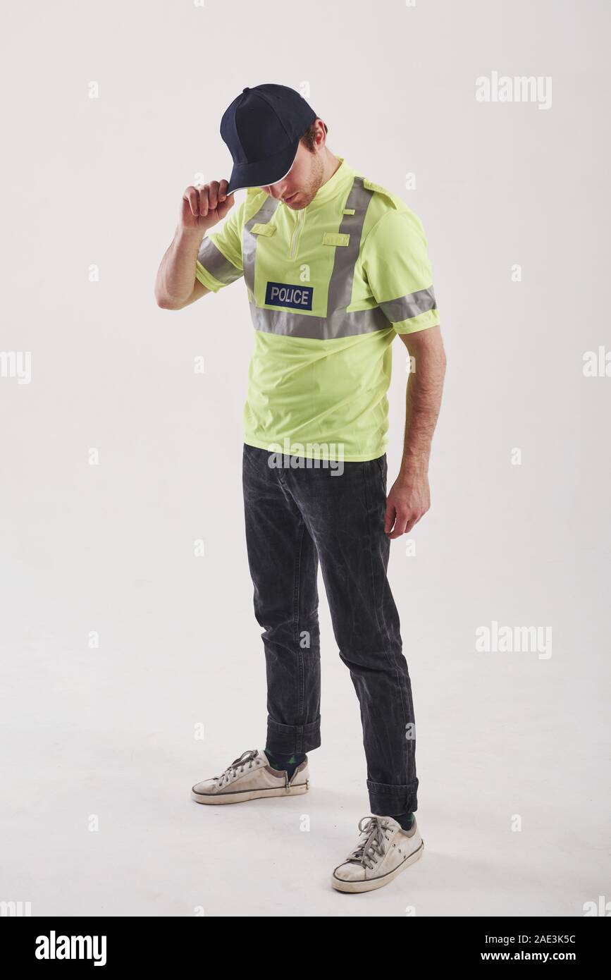 Hiding face behind the hat. Policeman in green uniform stands against ...