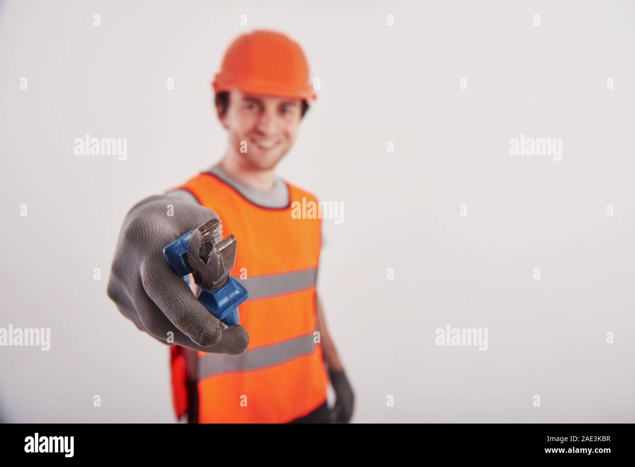 Take this tool. Man in orange colored uniform stands against white ...