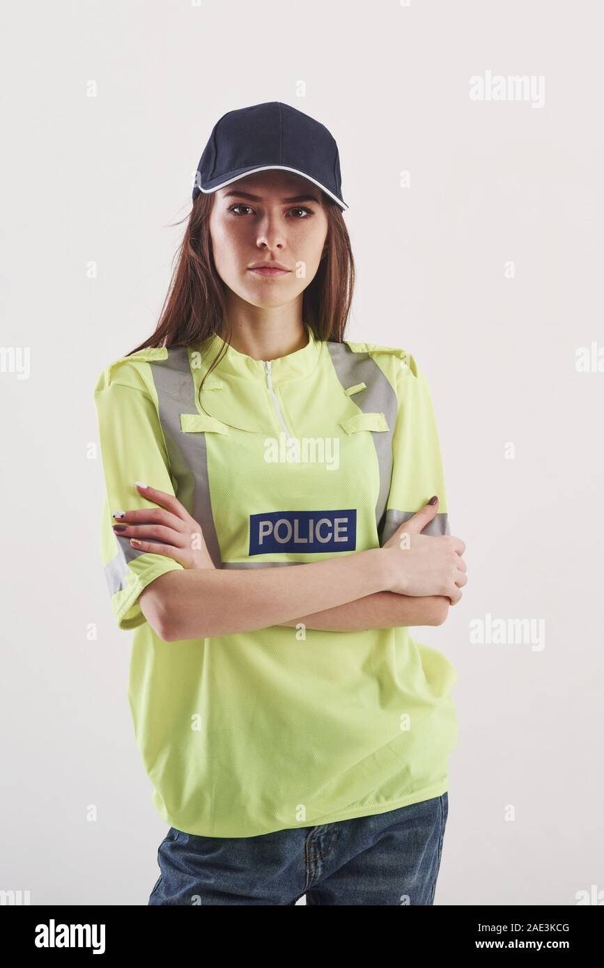 Pretty woman in green police uniform stands against white background in ...