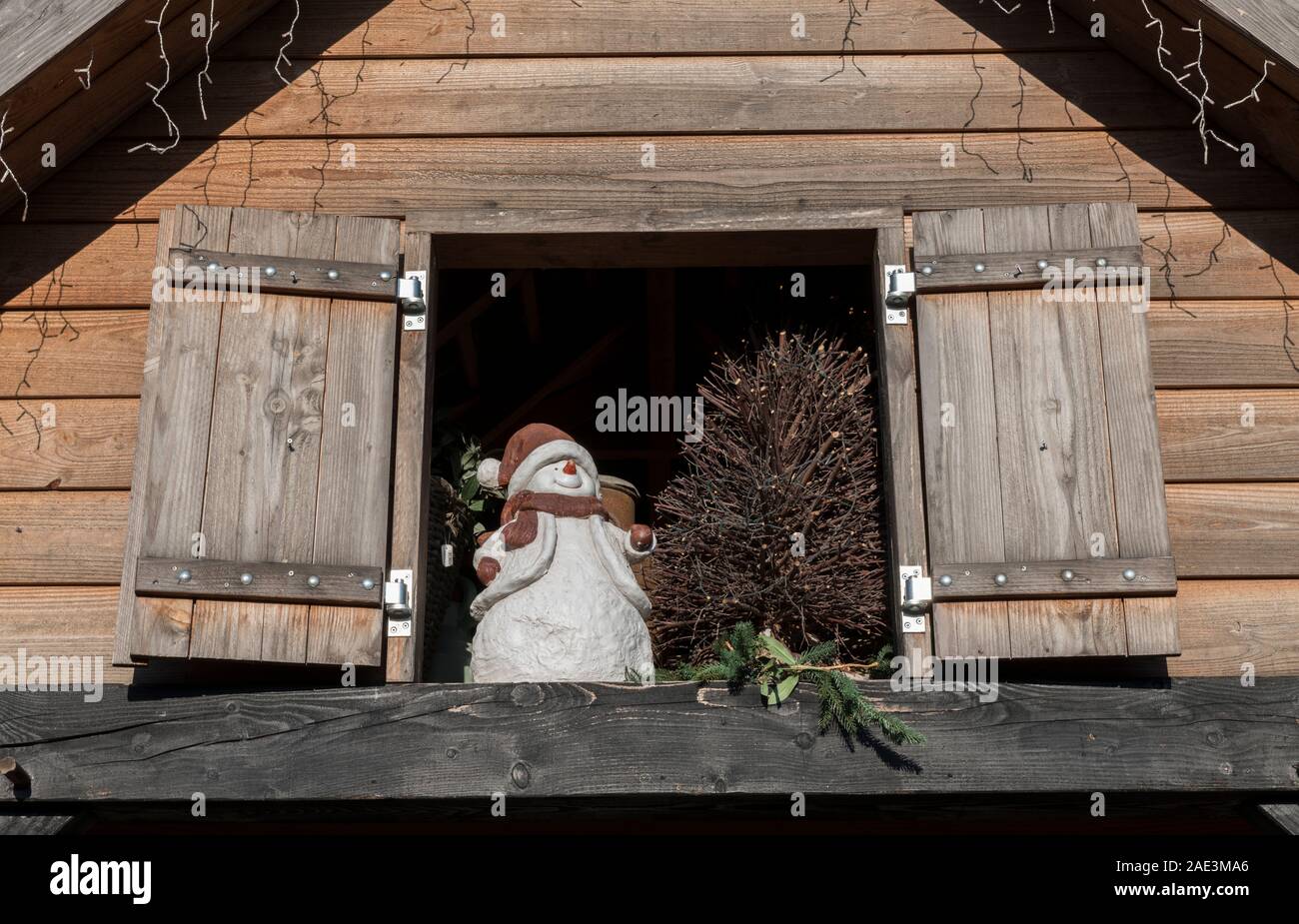 a decoration snowman with hat looking out of the window in a wooden ...
