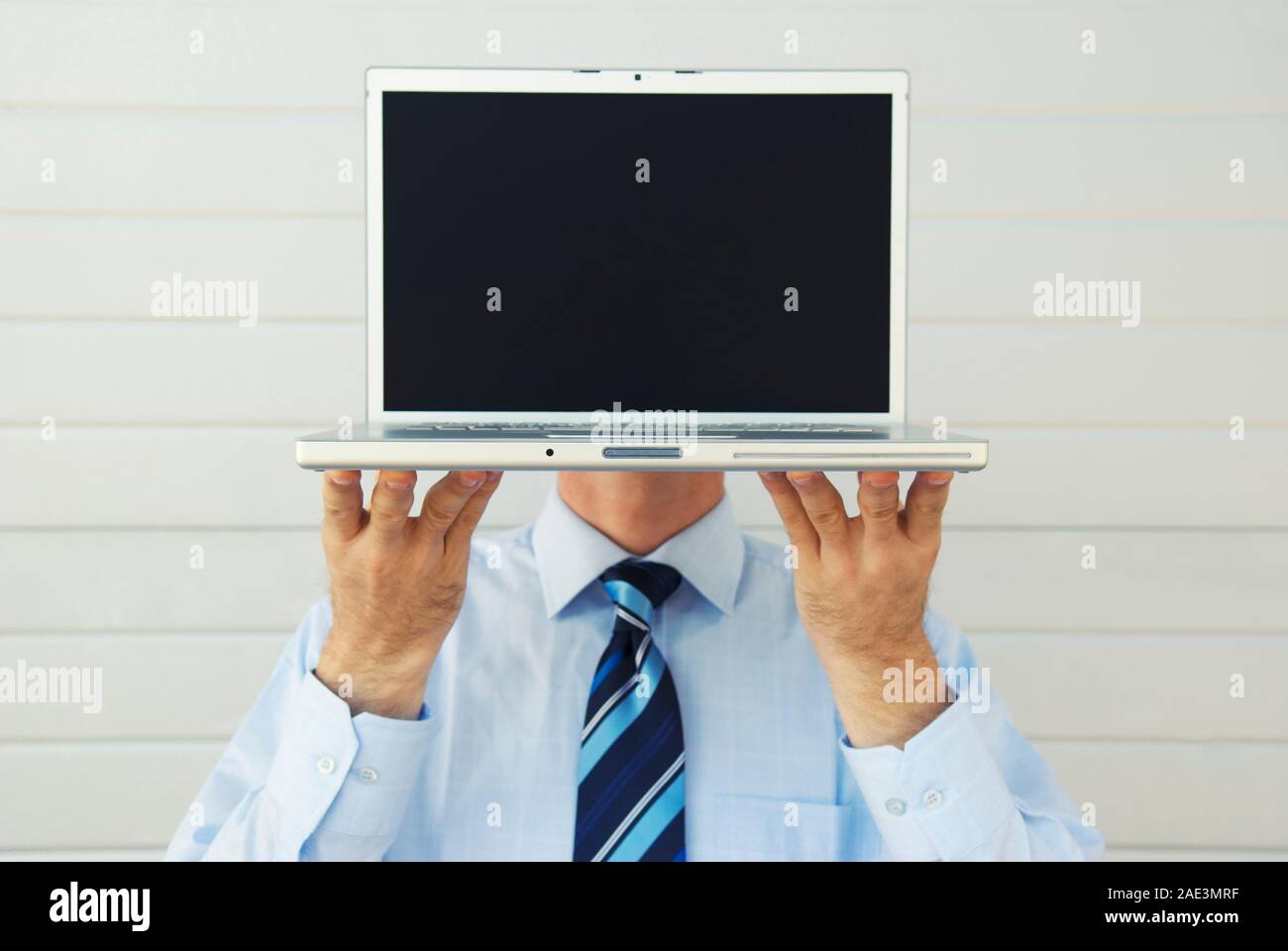 Unrecognizable businessman holding laptop computer in front of his head ...