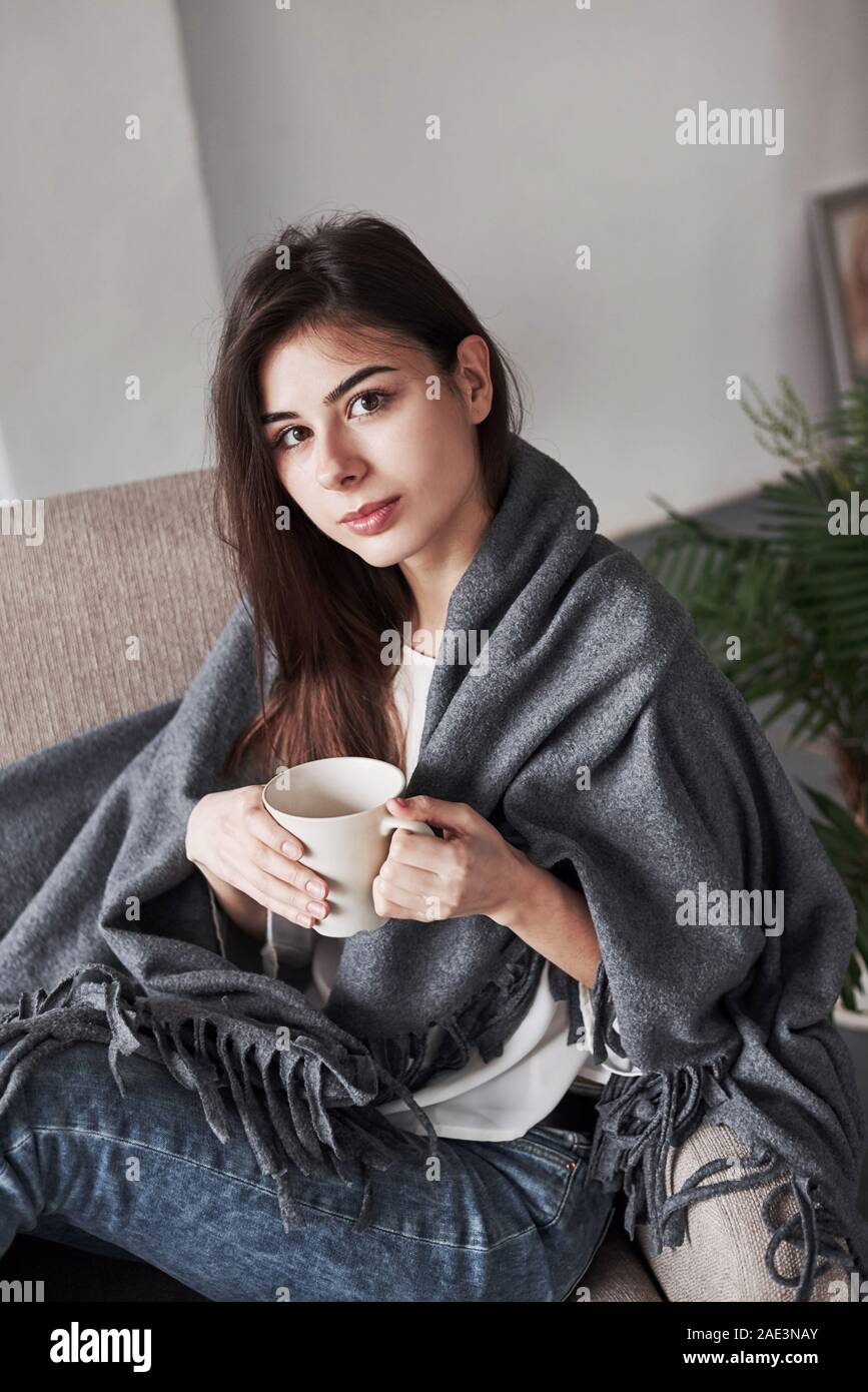 Struggle with coldnes by fresh hot beverage. Young brunette in the room ...