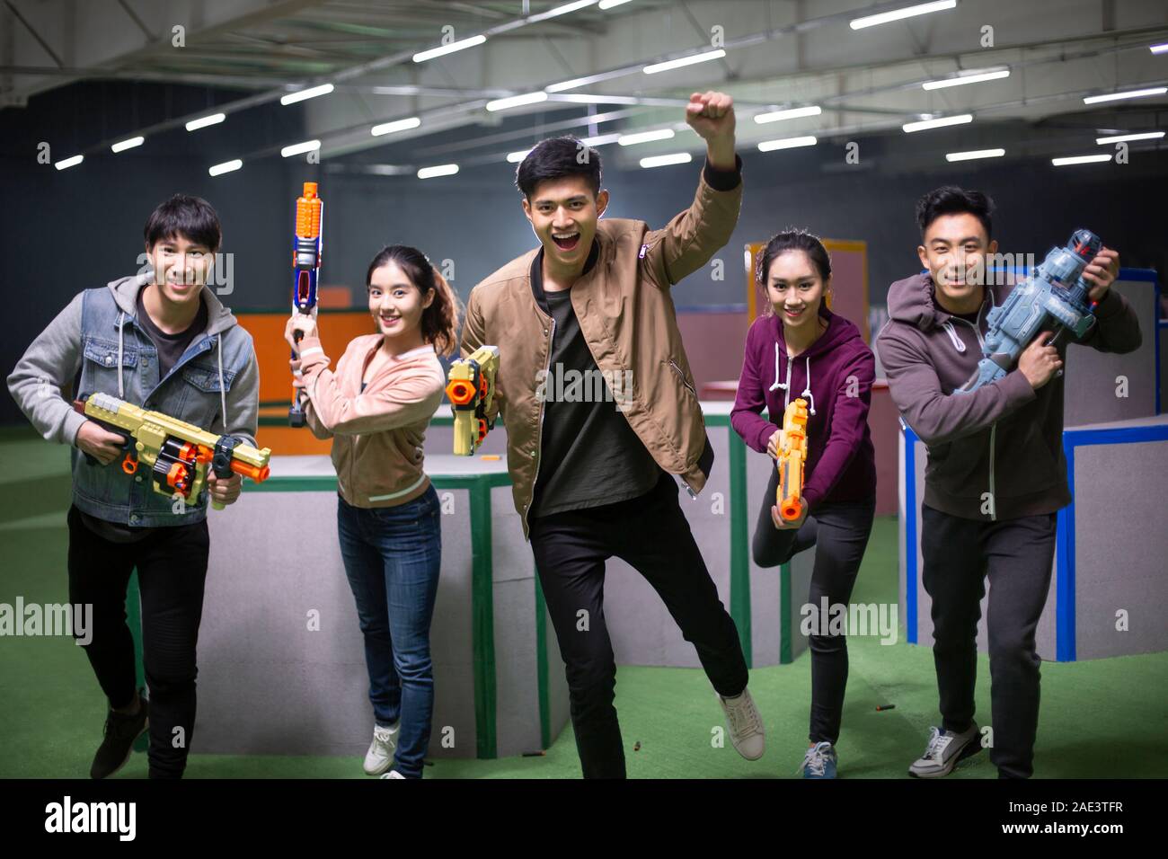 Happy young friends playing gun game Stock Photo - Alamy