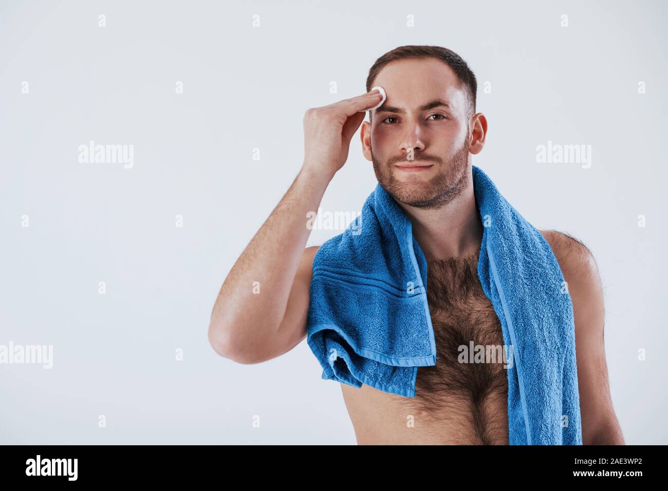 With bare chest. Man with blue towel stands against white background in ...