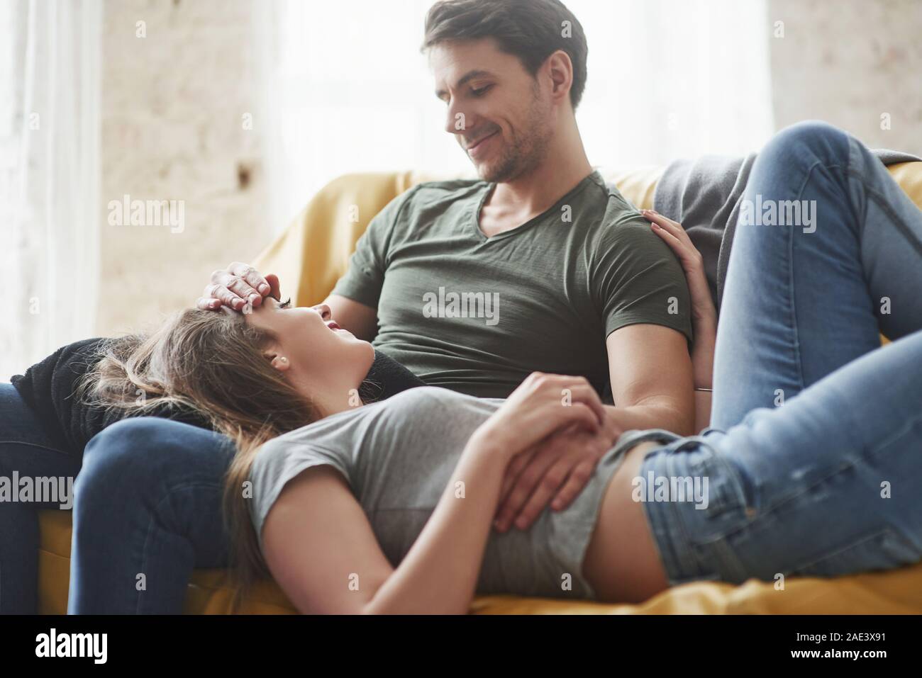 Two people having nice day. Happy couple relaxing on the yellow sofa in ...
