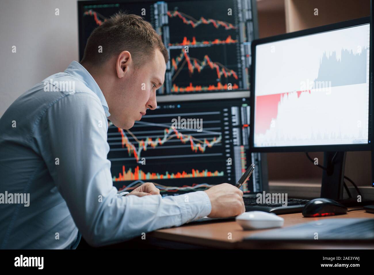 Doing his daily job. Man working online in the office with multiple ...