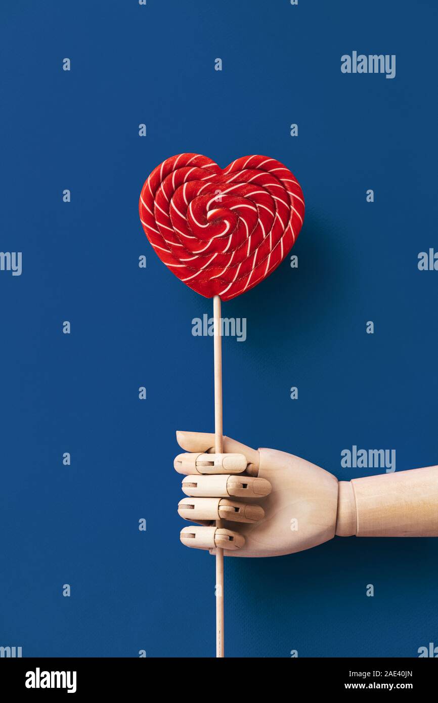 Wooden hand holding a large blue and white striped lollipop Stock Photo ...