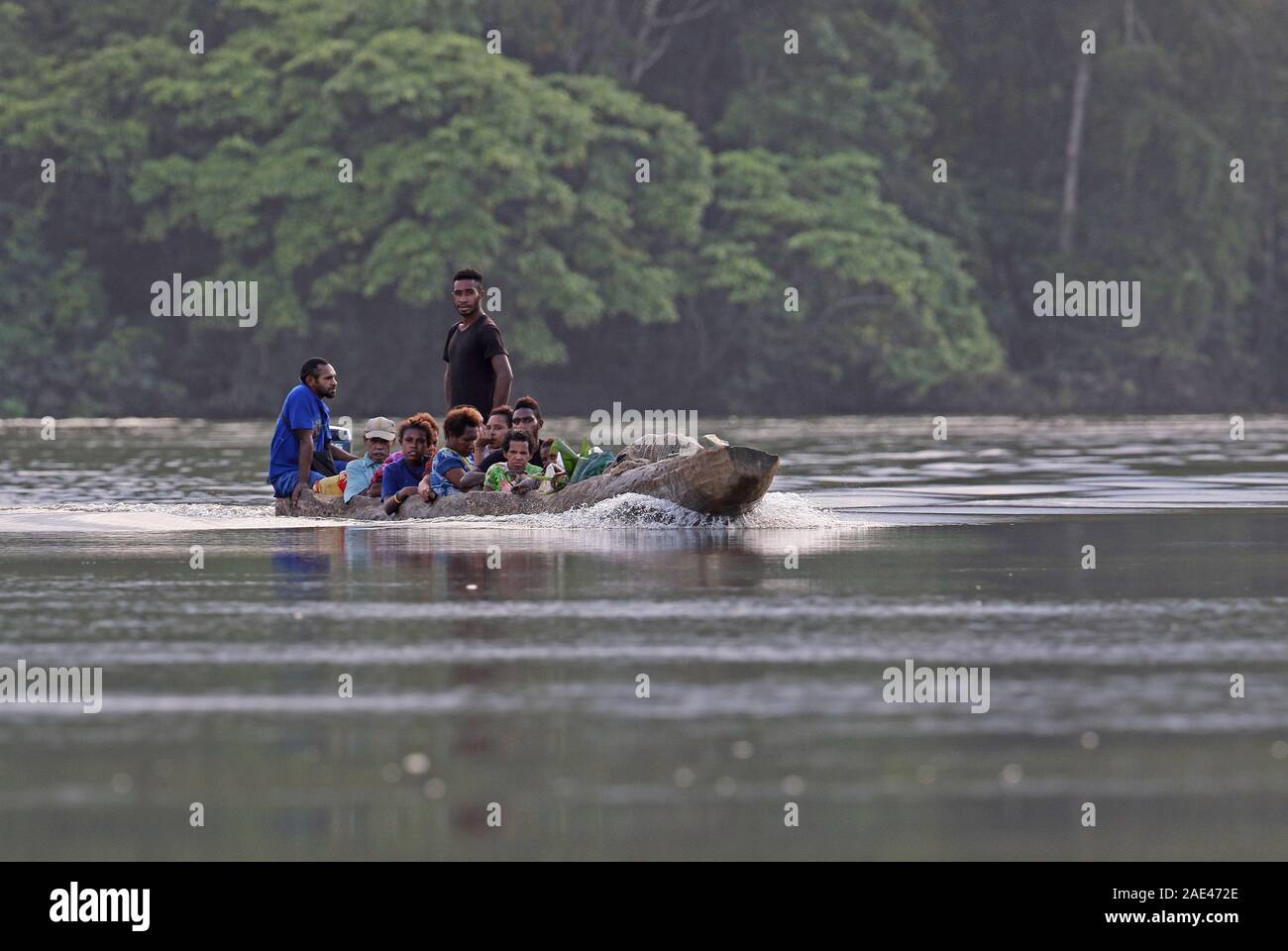 local villagers travelling by motorised dugout canoe Fly River, Papua ...
