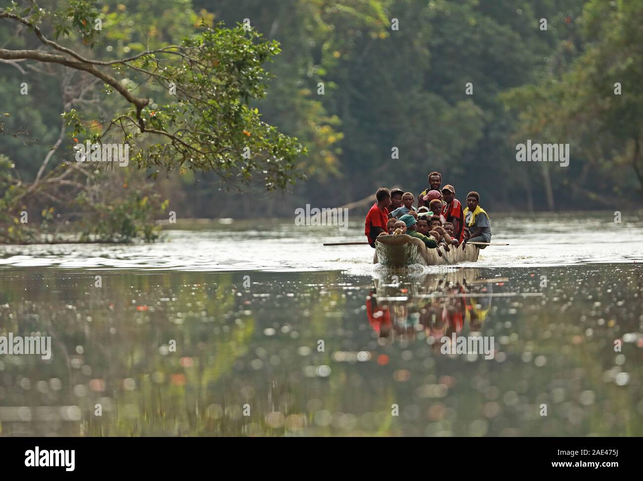local villagers travelling by motorised dugout canoe Fly River, Papua ...