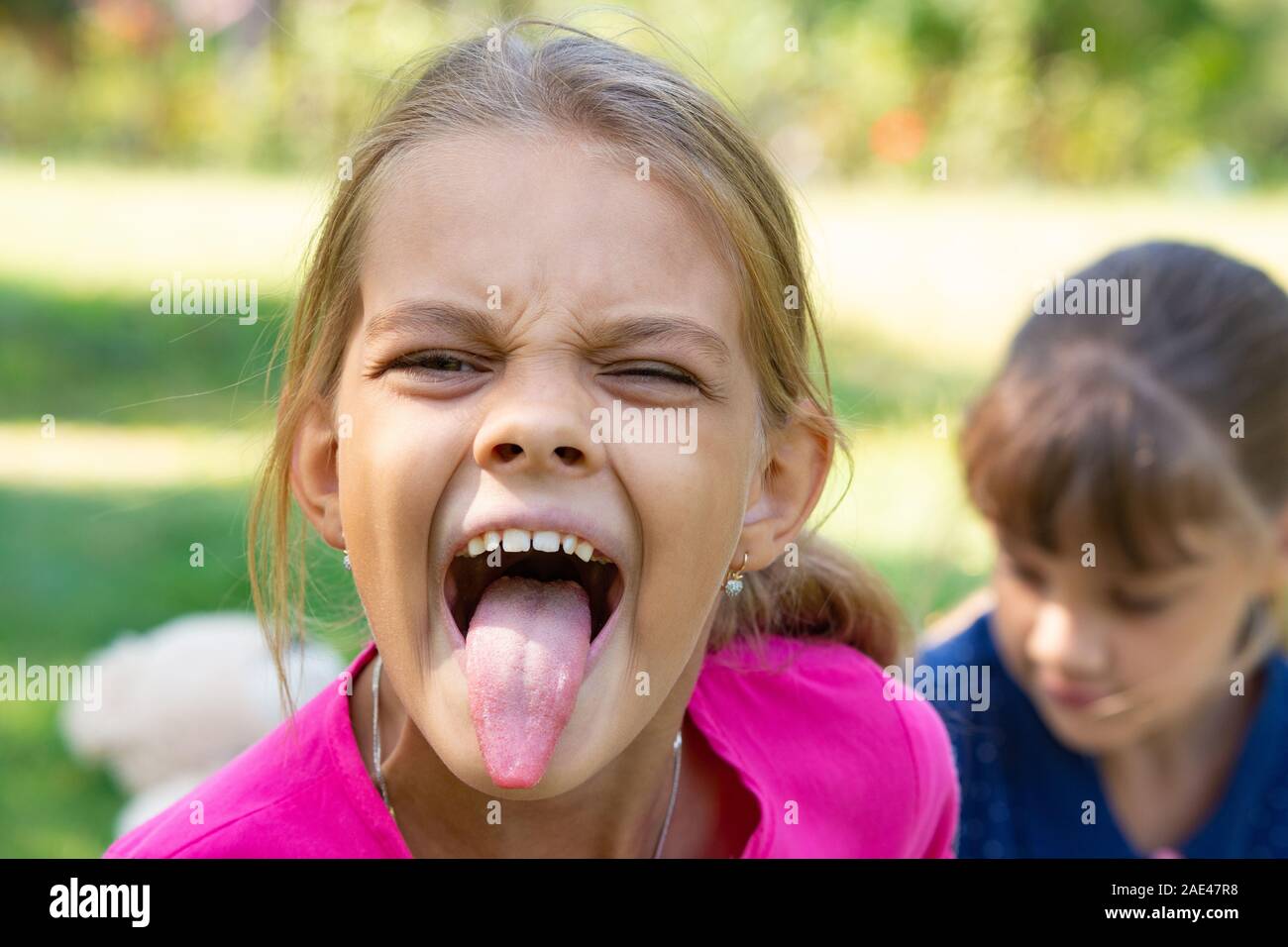 The girl turned and funny shows a long tongue Stock Photo - Alamy