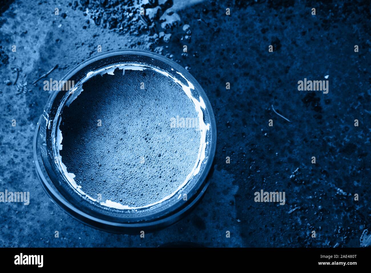 Spoiled white paint in a jar turned into a blue liquid with bubbles ...